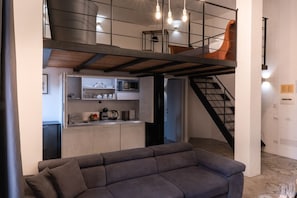 Um interior moderno com sofá, cozinha e escada.