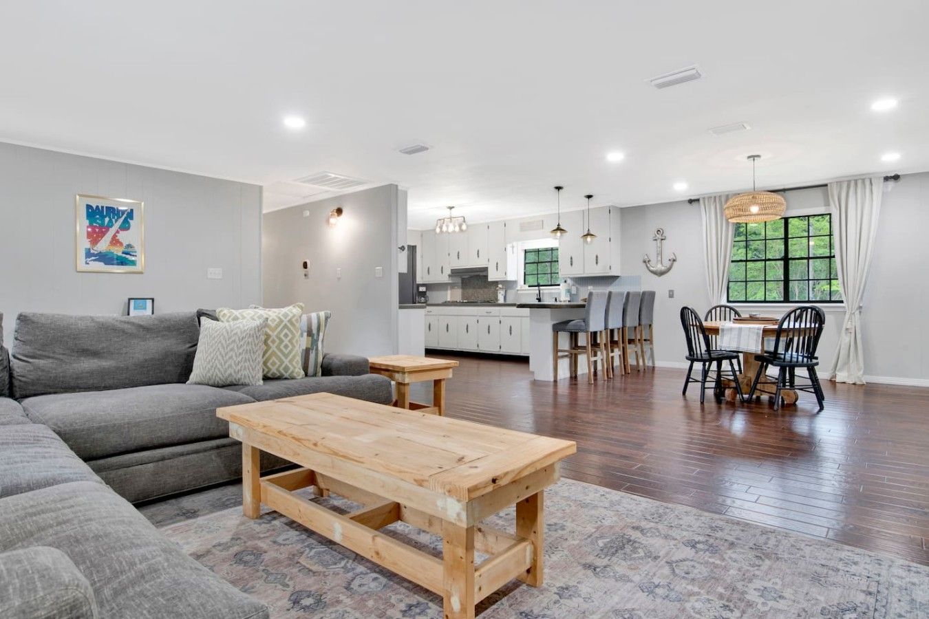 Uma sala de estar moderna com sofá, mesa de centro e área de jantar com cadeiras e uma mesa.