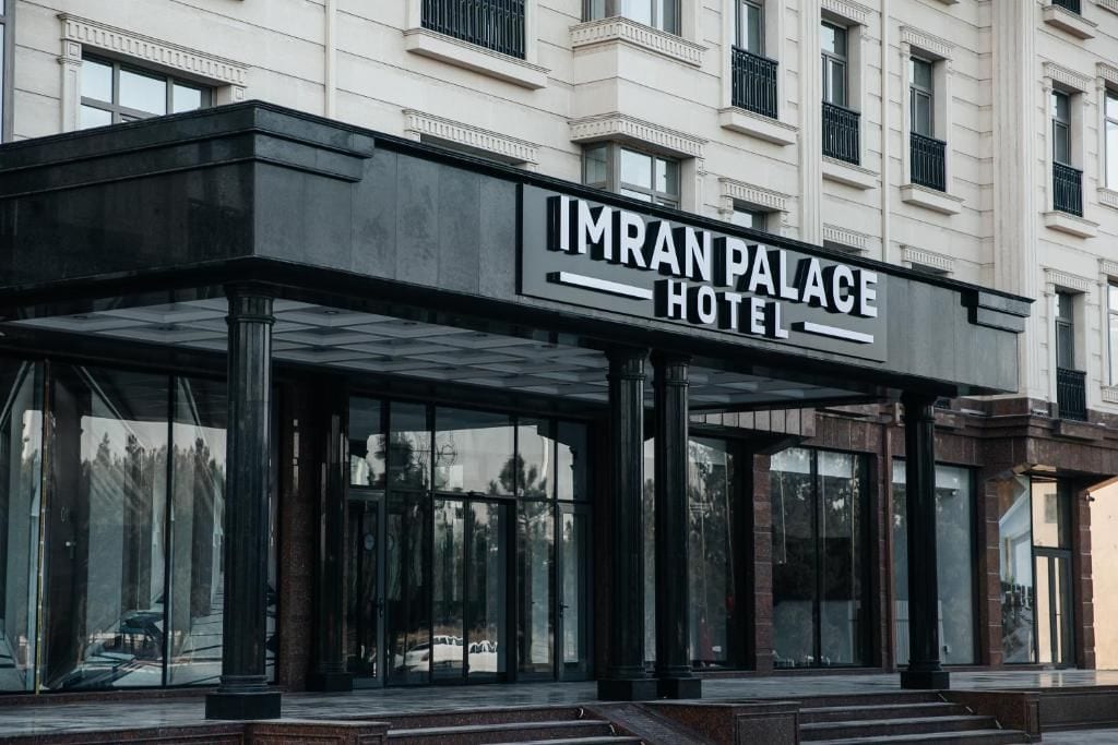 Entrada do HOTEL IMRAN PALACE com design moderno, destacando grandes portas de vidro e uma placa chamativa.