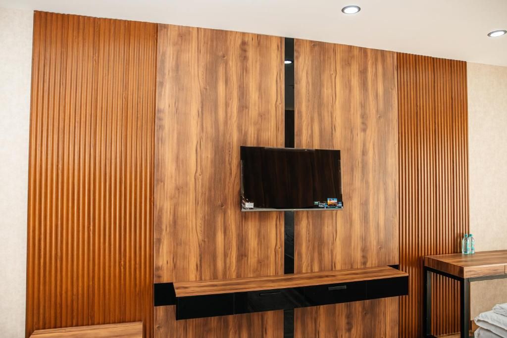 Quarto com parede de painel de madeira, TV de tela plana fixada nela e um banco de madeira.
