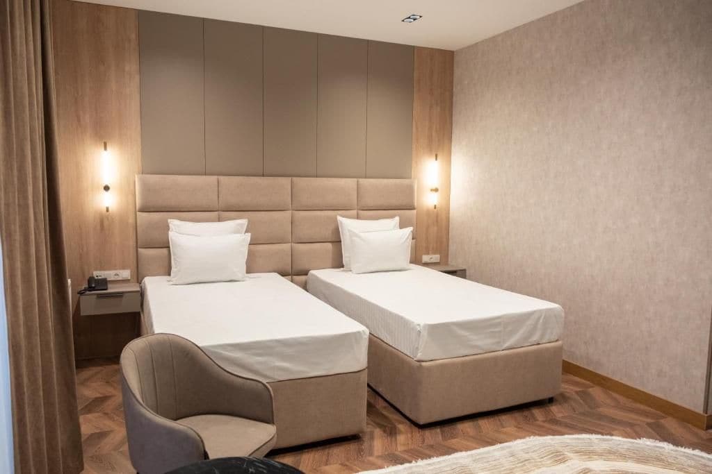 Quarto de hotel com duas camas, um sofá e uma mesa de cabeceira.