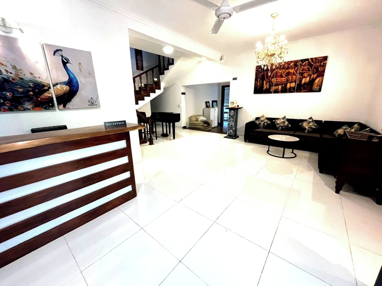 Uma sala de estar ampla com balcão de recepção, escada e lustre.