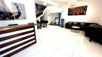 Uma sala de estar ampla com balcão de recepção, escada e lustre.