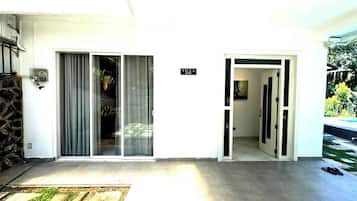 Uma casa moderna com parede de pedra, porta de vidro deslizante e pátio de concreto.