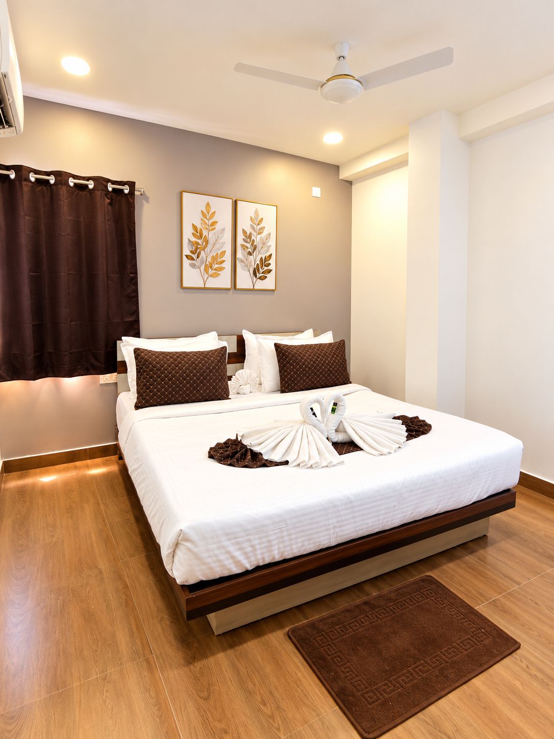 Quarto de hotel com cama, ventilador de teto, obras de arte na parede e tapete marrom.