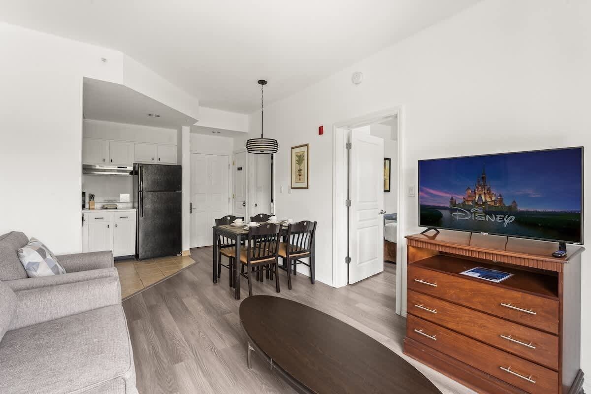 Um apartamento moderno com sala de jantar, cozinha compacta e sala de estar com televisão de tela plana.