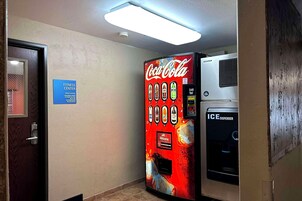 Máquina de refrigerantes Coca-Cola e dispensador de gelo em um corredor.
