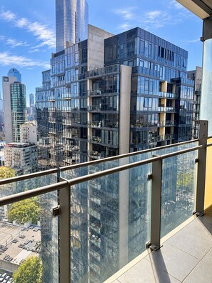 Um edifício alto com fachada de vidro, várias varandas e vista para a paisagem urbana.