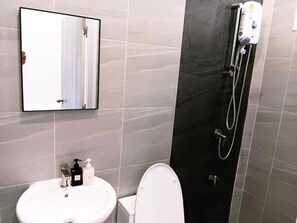 Casa de banho com lavatório branco, sanita, espelho e chuveiro com painel de comando.