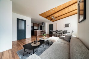 Uma sala de estar moderna com pé direito alto, área de jantar e cozinha.