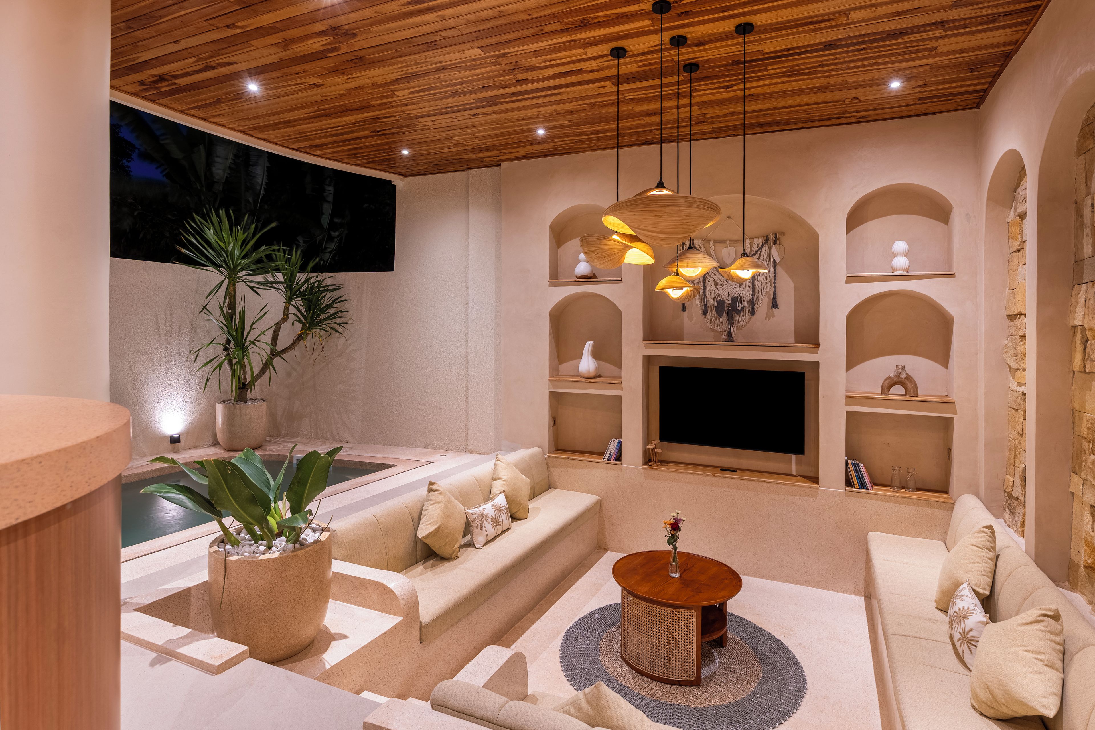 Uma sala de estar moderna com televisão de tela plana, assentos confortáveis e teto de madeira.