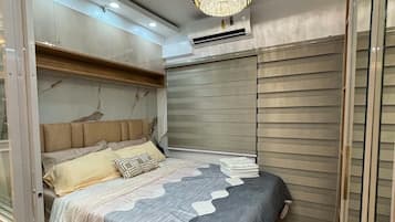 Quarto com cama, lustre e porta deslizante.