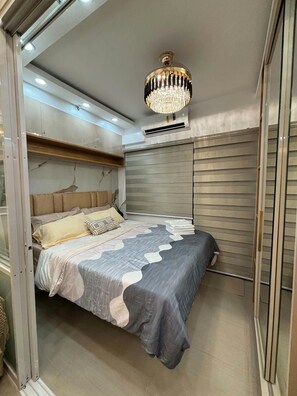 Quarto com cama, lustre e porta deslizante.