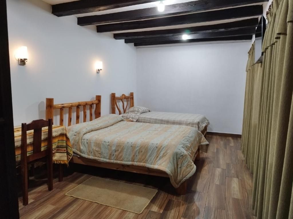 Quarto com duas camas, cabeceiras de madeira, uma cadeira e um tapete.