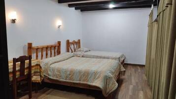 Quarto com duas camas, cabeceiras de madeira, uma cadeira e um tapete.