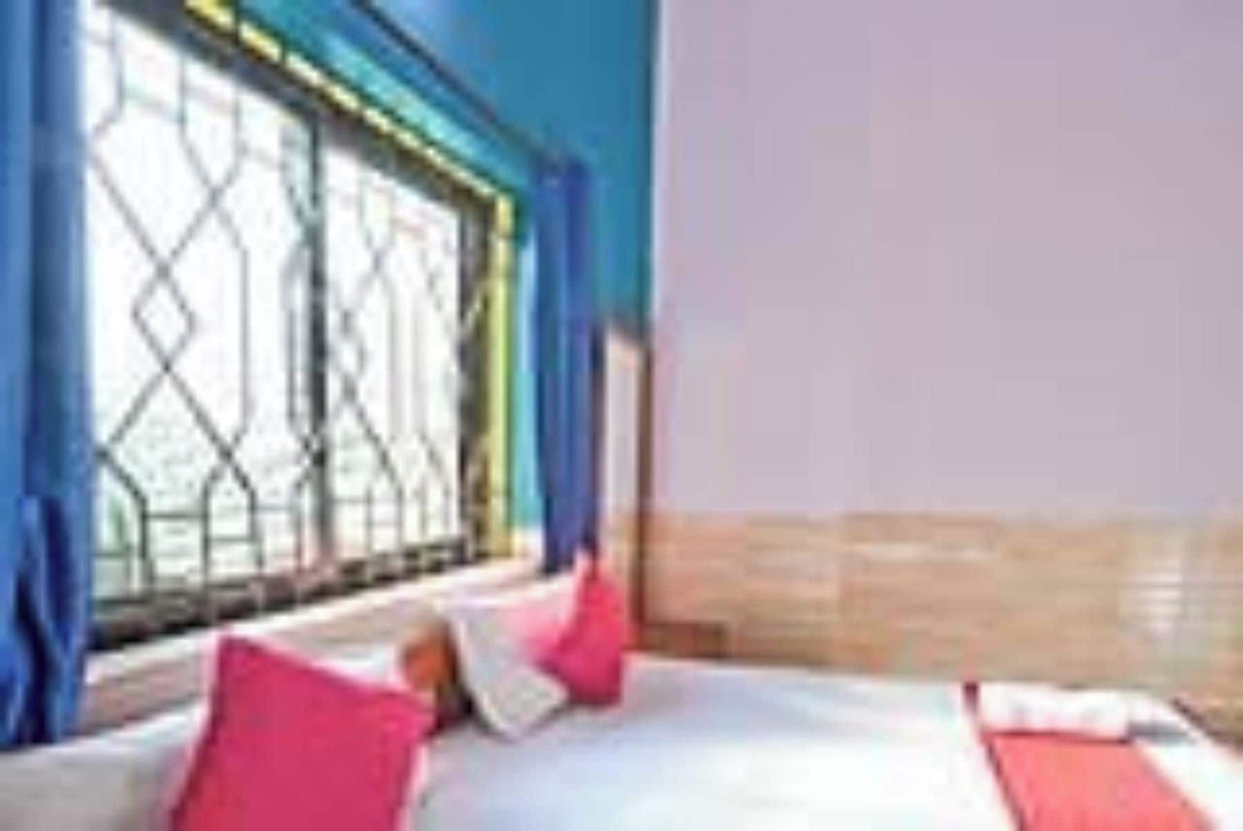 Quarto com cama, janela com grade decorativa e parede azul.