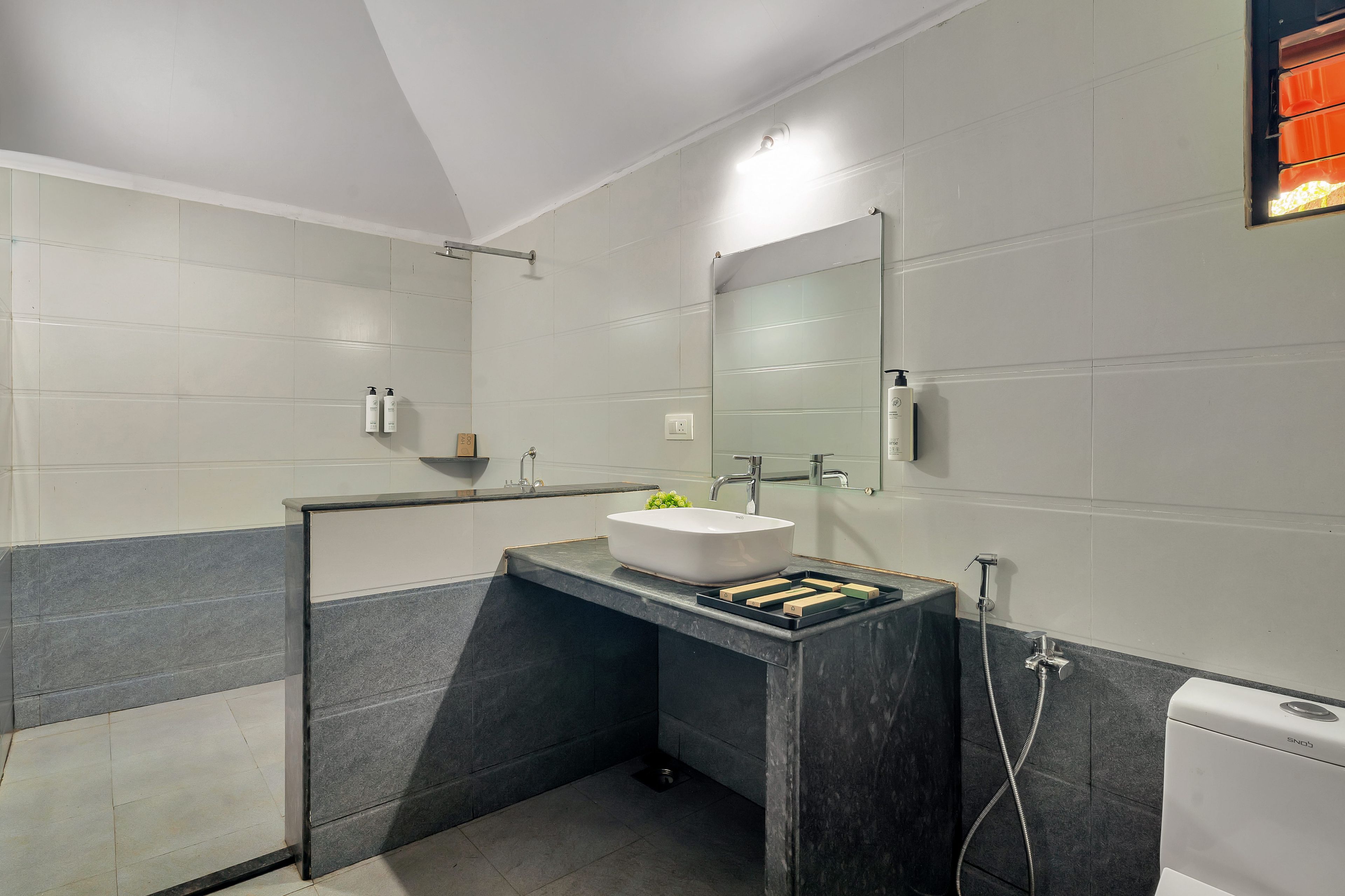Casa de banho moderna com lavatório branco, espelho e chuveiro.