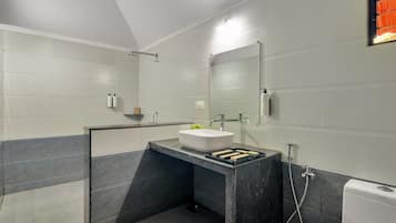 Casa de banho moderna com lavatório branco, espelho e chuveiro.