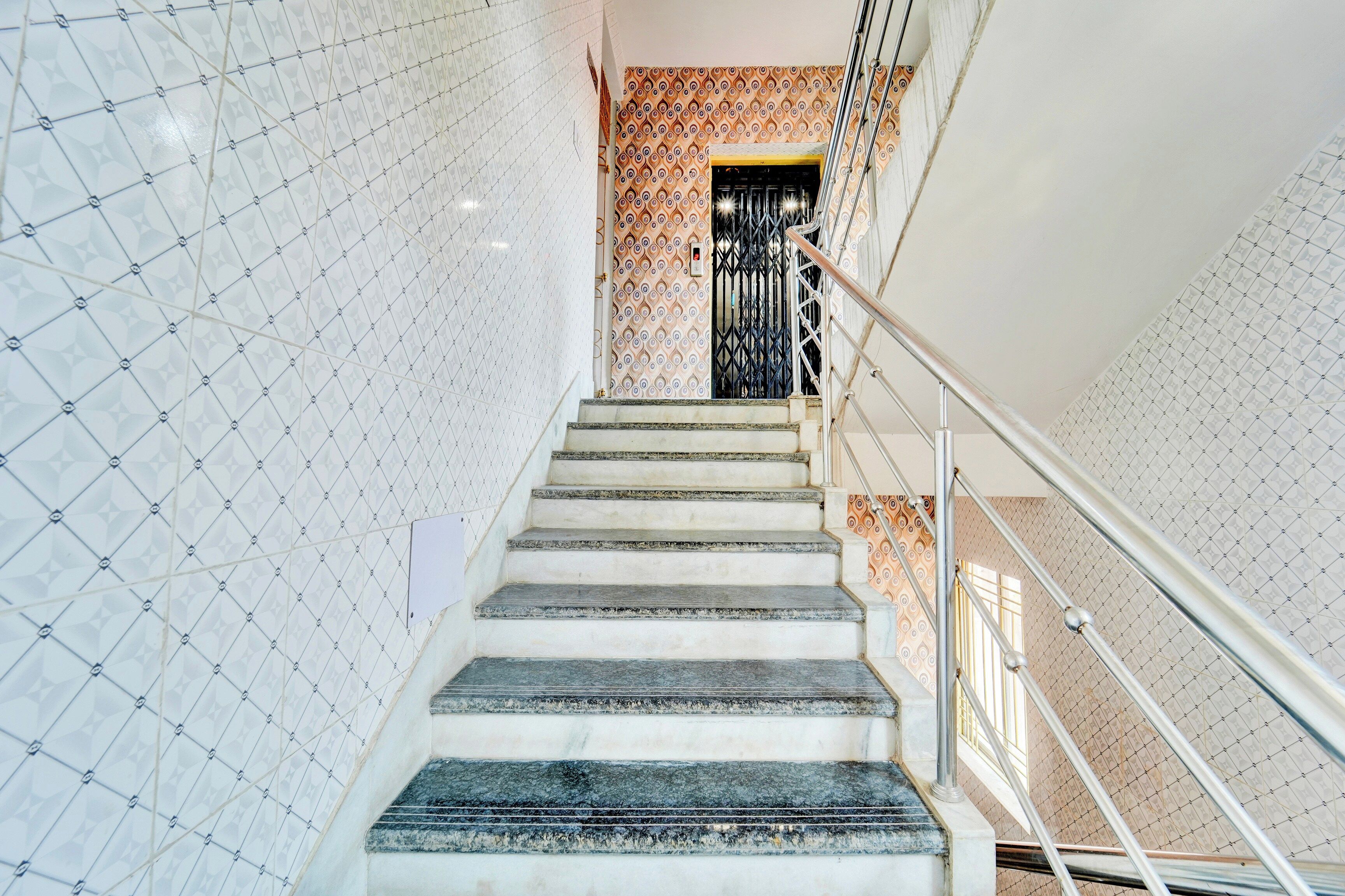 Uma escadaria com degraus de mármore conduzindo a uma porta, com um padrão geométrico nas paredes.