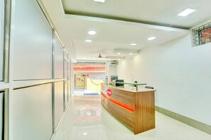 Balcão de recepção com design moderno, um ventilador de teto e vista para um portão vermelho ao fundo.
