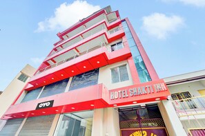 Um hotel com vários andares, varandas e um letreiro chamativo com a inscrição 'HOTEL SHAKTI INN'.