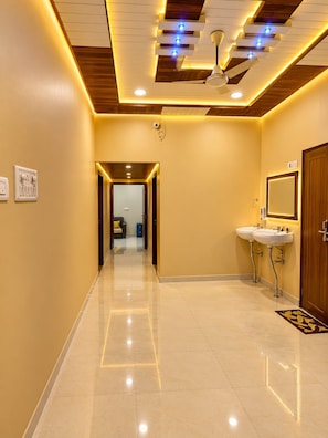 Corredor de hotel com design moderno, com ventoinha no teto, iluminação embutida e piso limpo e polido.