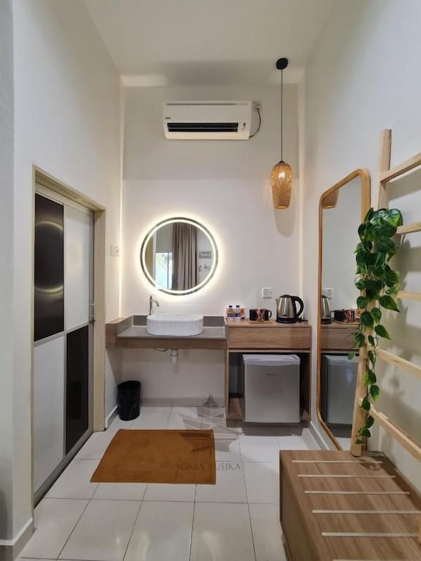 Uma casa de banho moderna com um espelho redondo, uma pia, um pequeno armário e uma planta.