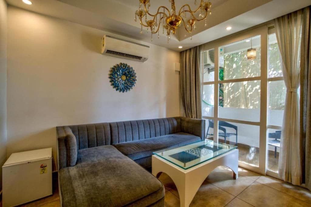 Uma sala de estar com sofá, mesa de centro de vidro e lustre.