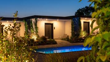 Um edifício moderno com piscina, área de estar ao ar livre e vegetação.