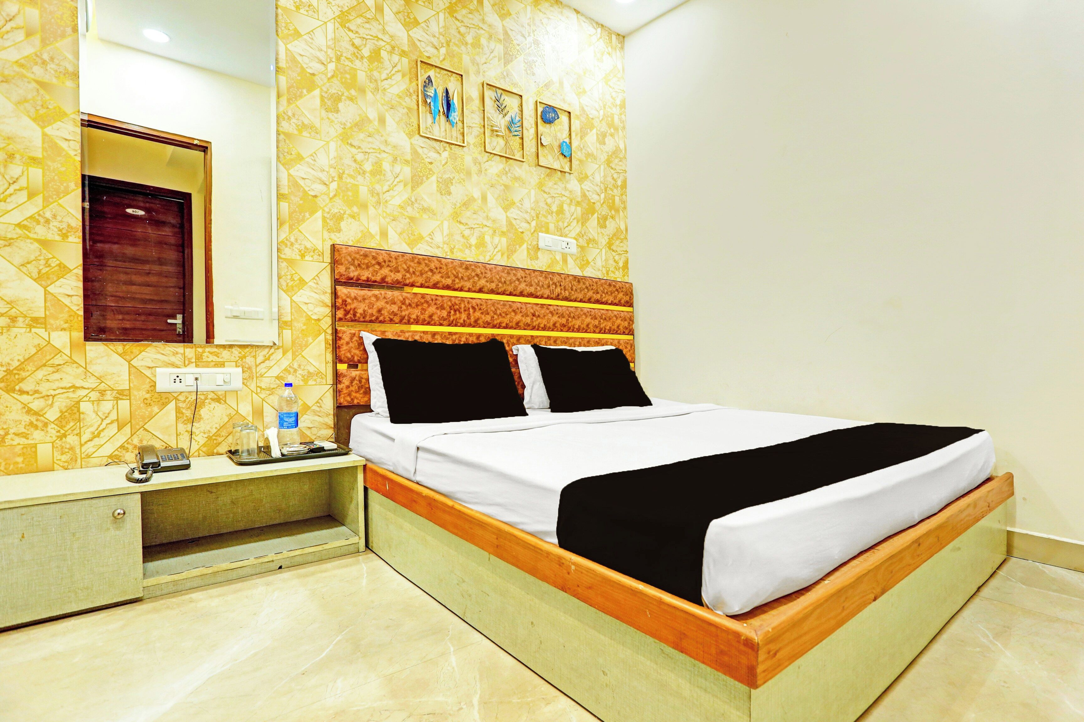 Quarto de hotel com cama, mesa de cabeceira e espelho.
