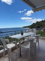 Terraço ao ar livre com mesa e cadeiras, com vista para a costa.