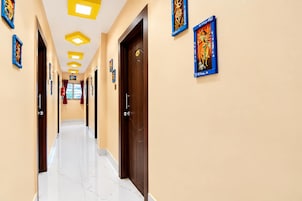 Corredor de hotel com piso de mármore, portas de madeira e obras de arte emolduradas nas paredes.