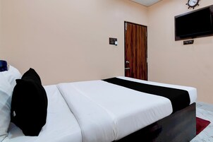 Quarto de hotel com cama, televisão fixada na parede e porta.