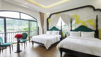 Quarto de hotel com duas camas, uma varanda com vista e uma mesa com um vaso de flores.