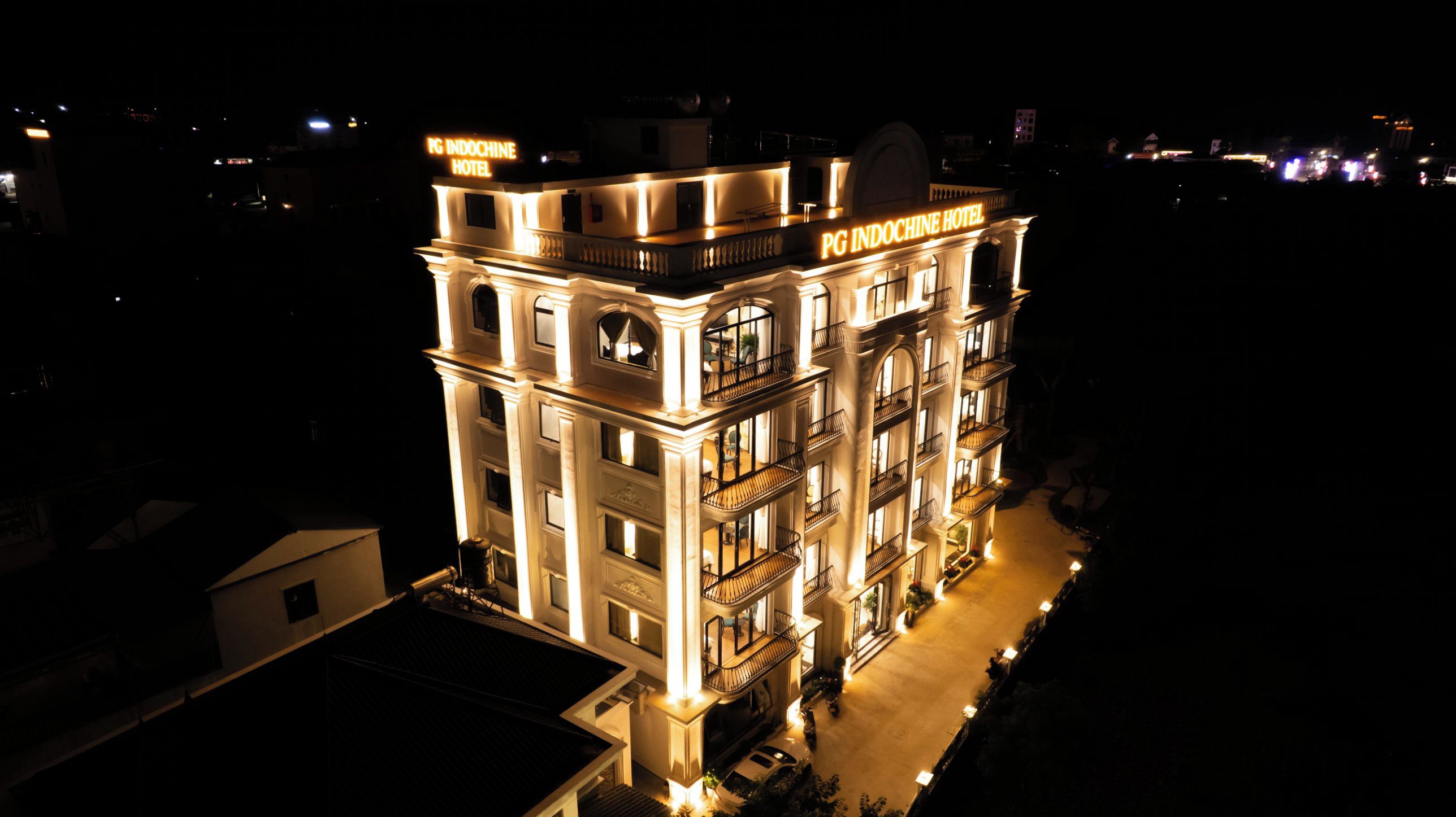 Um hotel com vários andares, fachada iluminada, varandas e entrada bem iluminada.