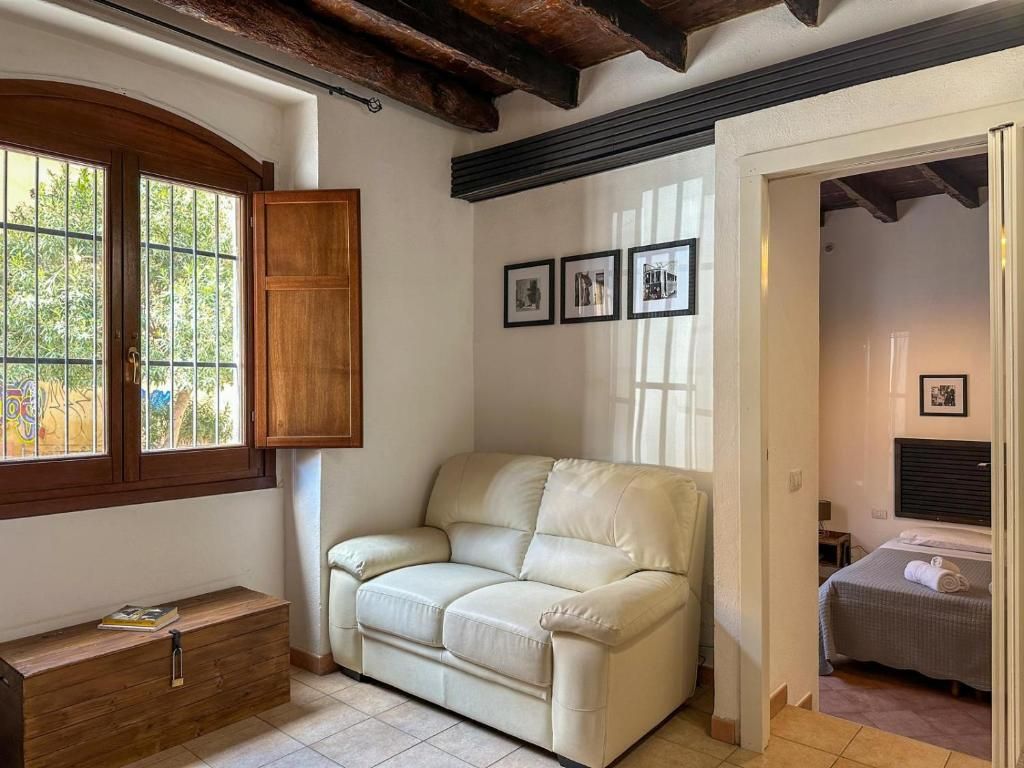 Quarto com sofá bege, armário de madeira e quadros nas paredes.