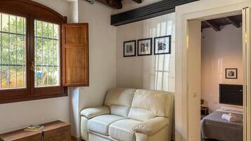 Quarto com sofá bege, armário de madeira e quadros nas paredes.