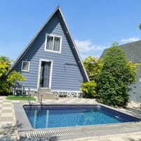 Um imóvel residencial com piscina, telhado triangular e gramado bem cuidado.