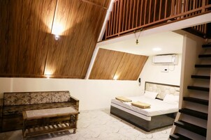 Quarto com cama, um banco e escada.