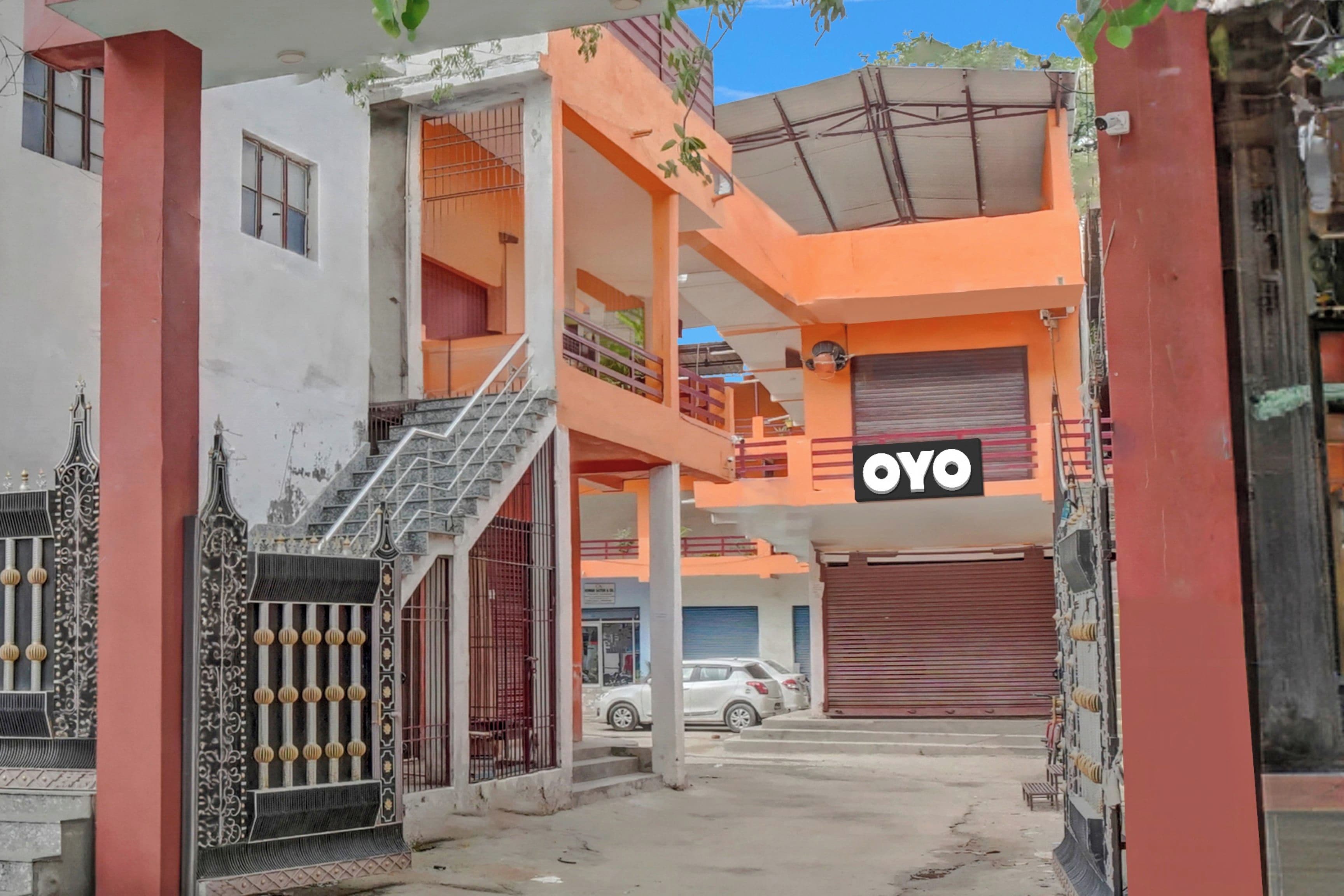 Um edifício de vários andares com escadaria, entrada gradeada e uma placa com a inscrição 'OYO'.