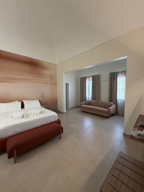 Quarto de hotel com cama, sofá e uma pequena mesa.