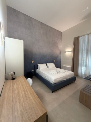 Quarto moderno com cama grande, mesas de cabeceira, escrivaninha e um espelho amplo.