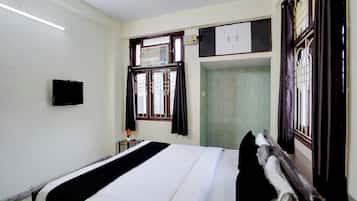 Quarto de hotel com cama, televisão de tela plana, janela com cortinas e armário.
