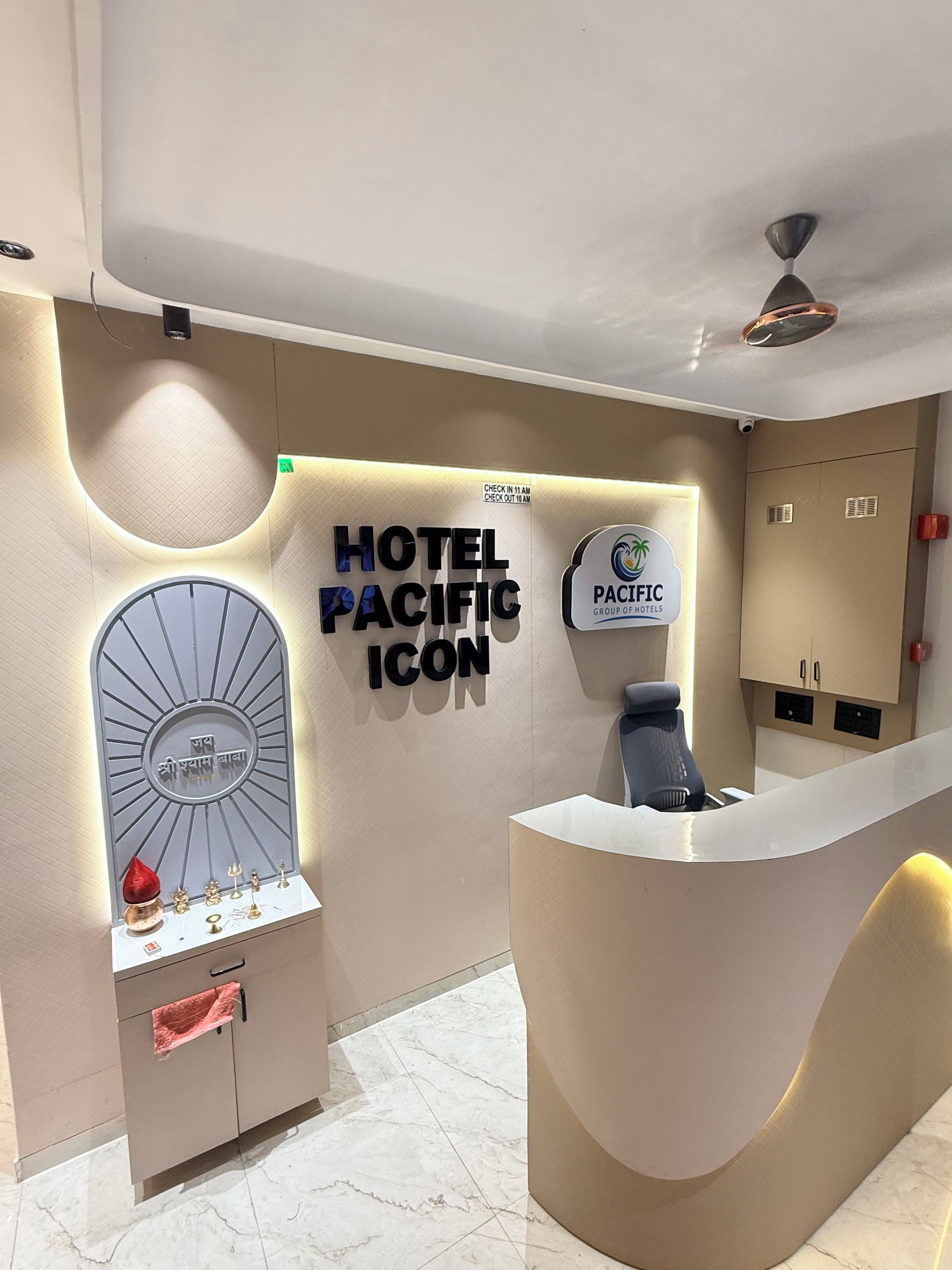 Um balcão de recepção com uma placa indicando 'HOTEL PACIFIC ICON' e o logotipo do Grupo Pacific Hotels.