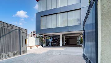 Edifício moderno com área de estacionamento coberta e entrada gradeada.