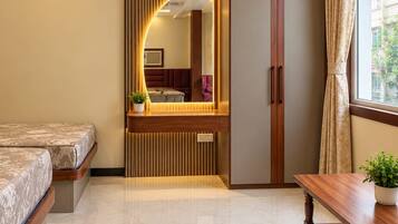 Quarto de hotel com cama, escrivaninha, espelho e guarda-roupa.
