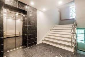 Um interior moderno com escada, elevador de vidro e um sofá.