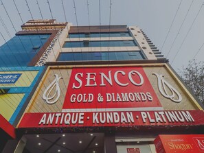 Um edifício com uma placa chamativa para 'Senco Gold & Diamonds' e 'Antique, Kundan, Platinum', indicando uma joalheria.