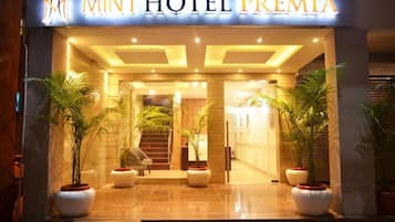 Entrada do Mint Hotel Premia, com design moderno, apresentando um balcão de recepção, uma escadaria e plantas em vasos.