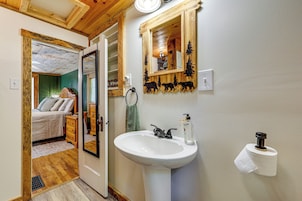 Casa de banho com lavatório branco, espelho e suporte para rolo de papel higiénico.
